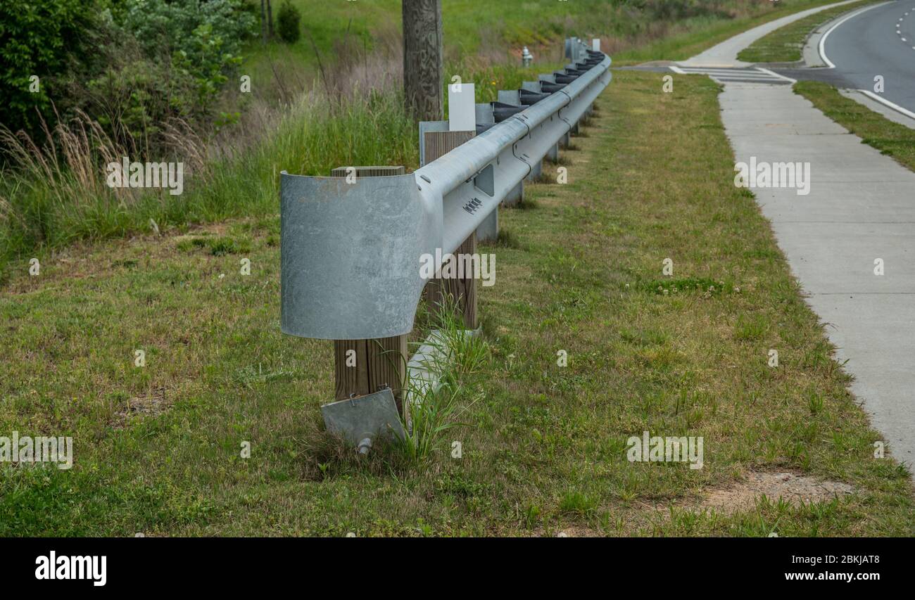 A short span of highway guard rail alongside the sidewalk and highway ...