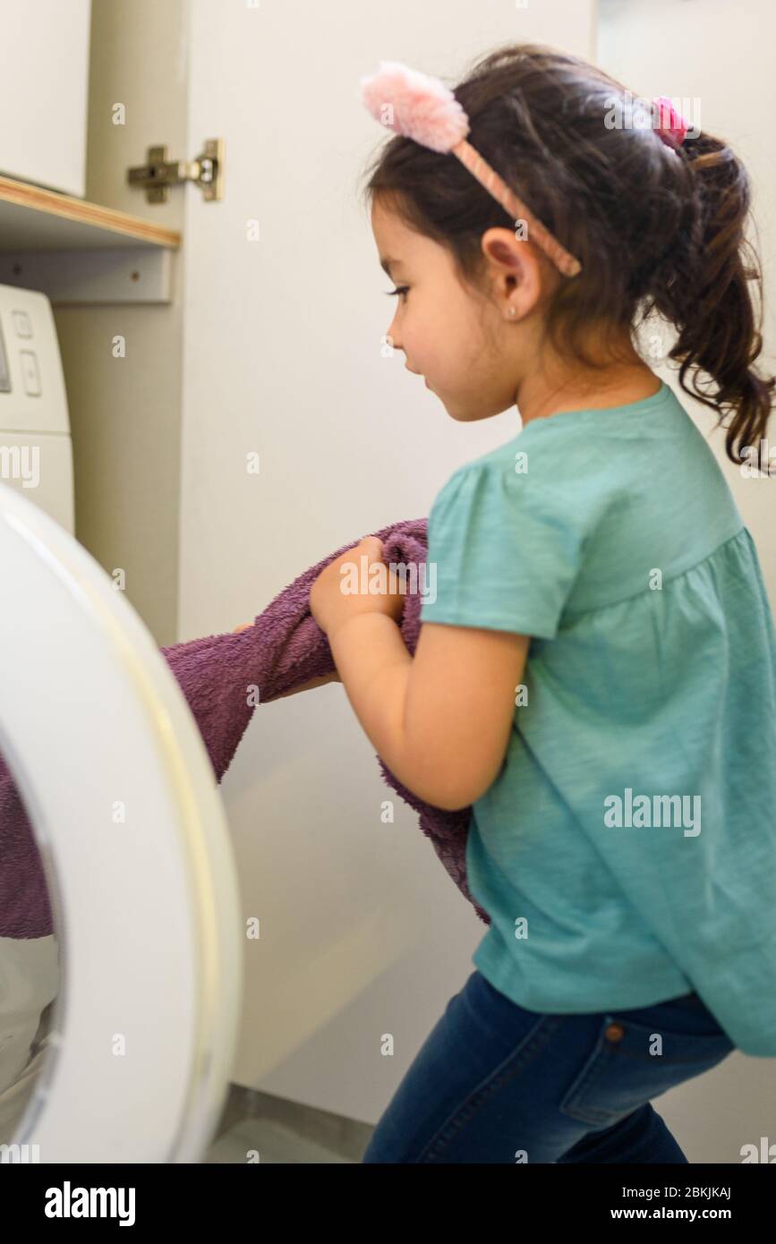 Little girl does laundry. Small child sorting clothes from the washing ...