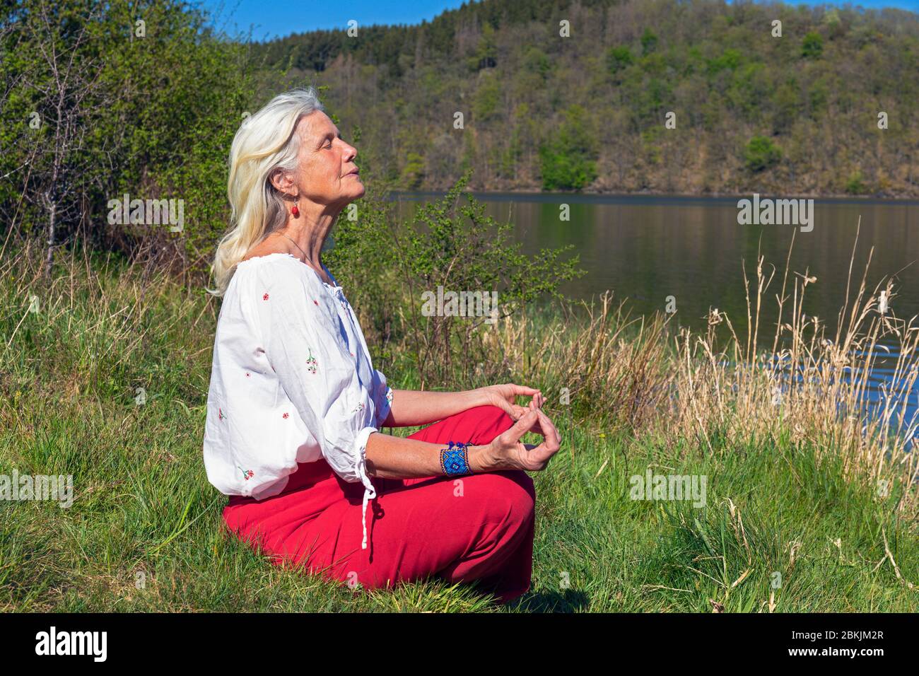 Europe, Luxembourg, Insenborn, Attractive older woman meditating by Lac ...