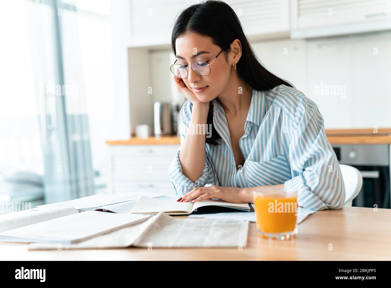 Image of a concentrated brunette young woman at the kitchen indoors at ...
