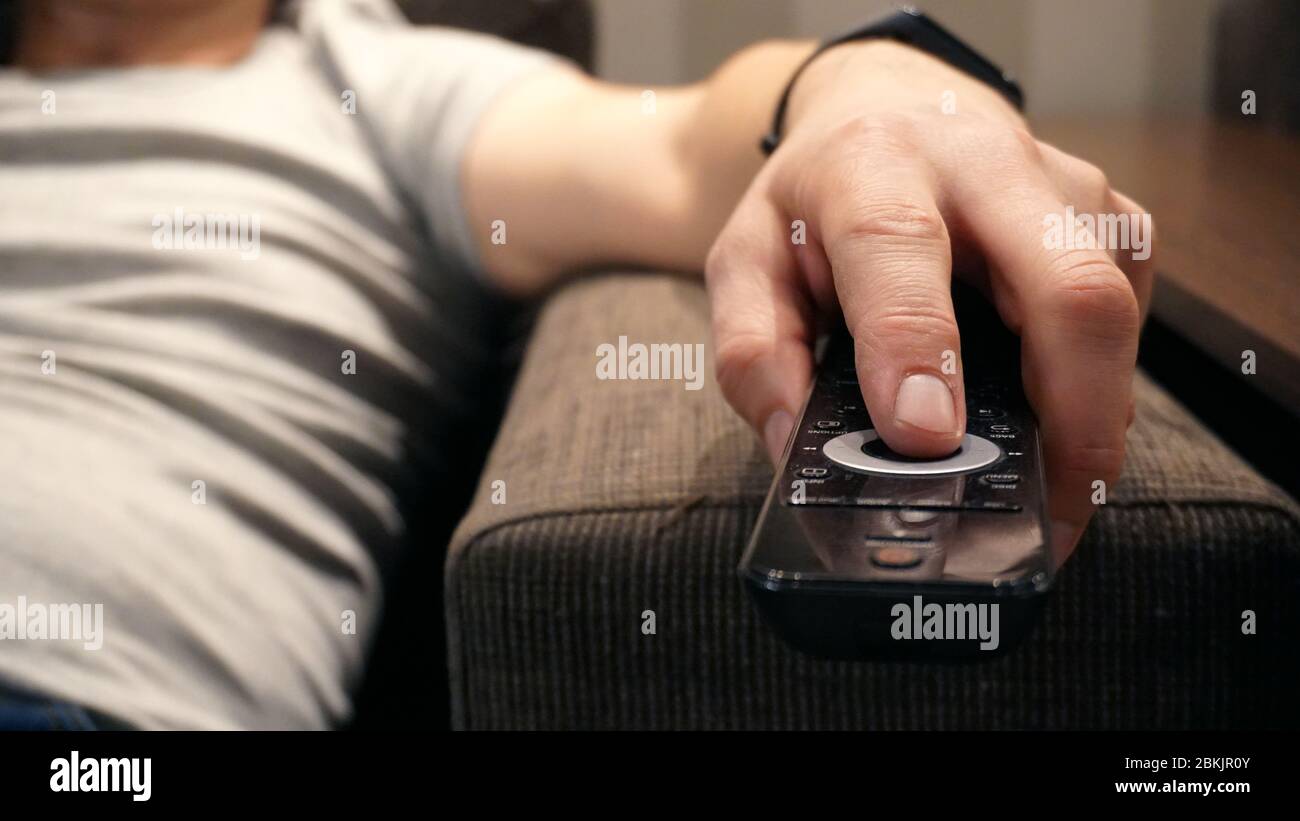 Men's hand with TV remote control. Relax man after work Stock Photo - Alamy
