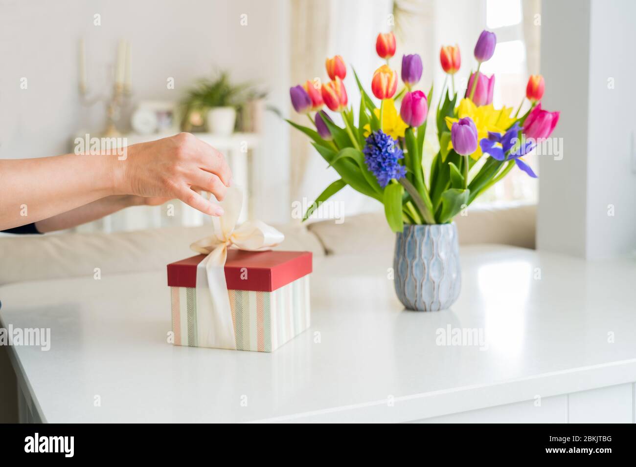 Close up woman opening gift box on marble table with colorful spring ...