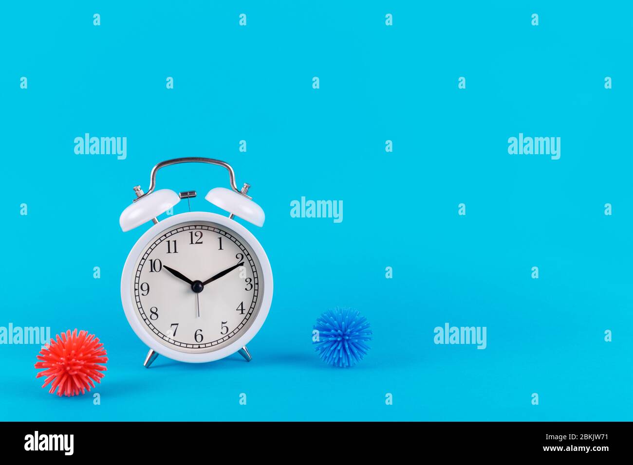 Alarm clock and plastic balls aka viruses on blue backdrop. Epidemic ...