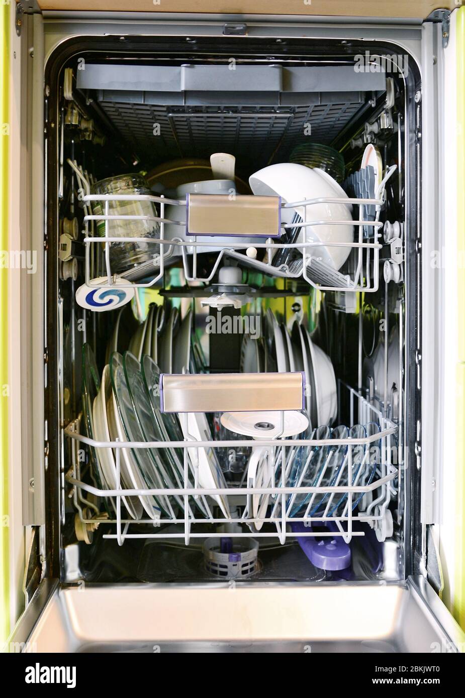 Front view into opened dishwasher full loaded of dishes. Full frame ...