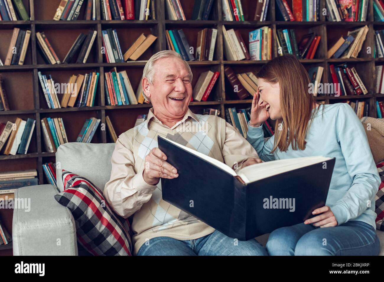 Father and daughter at home library sitting holding album laughing at ...