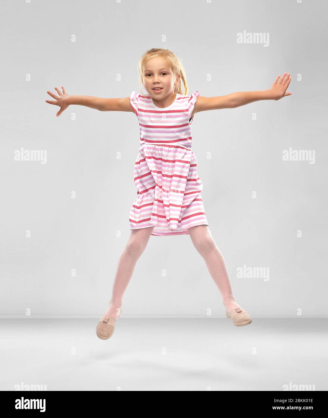 happy little girl in striped dress jumping Stock Photo - Alamy