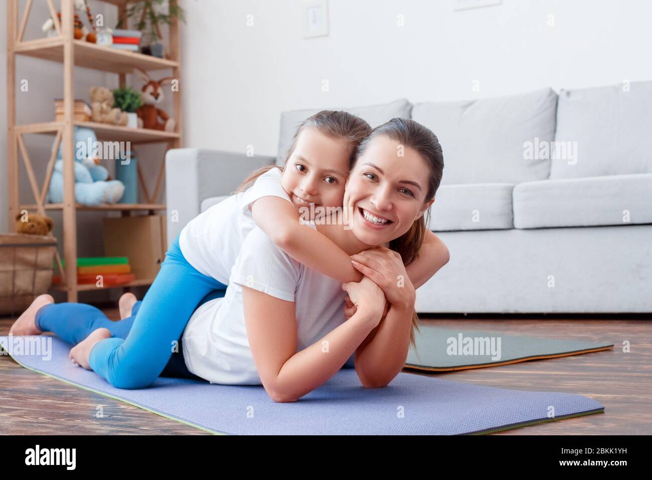 Healthy Lifestyle. Young daughter sitting on mother's back hugging her ...