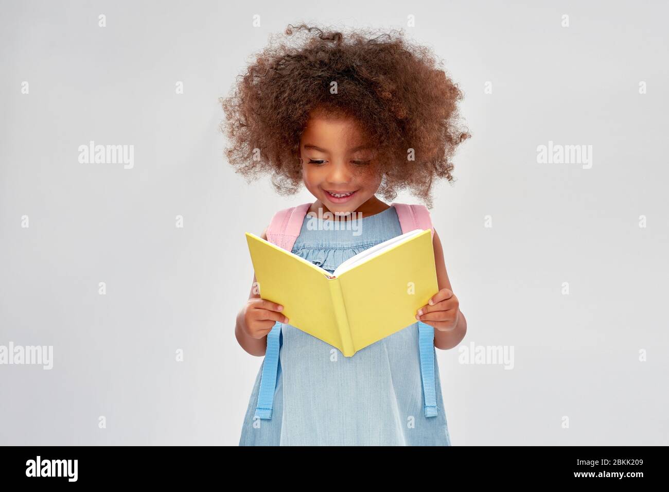 happy little african girl reading book Stock Photo - Alamy