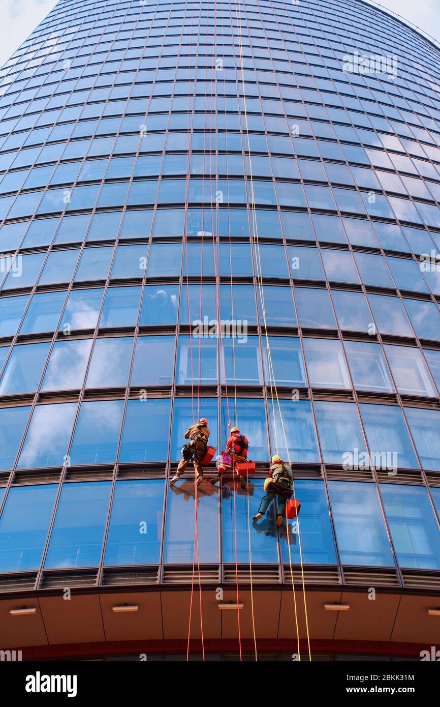 Three men workers in red and dark work clothes cleaning the exterior ...