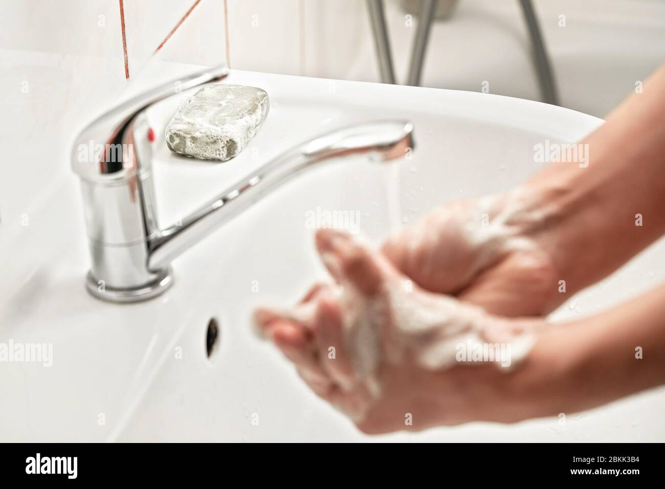 Young man washing hands under tap water with soap, focus on soapbar in ...