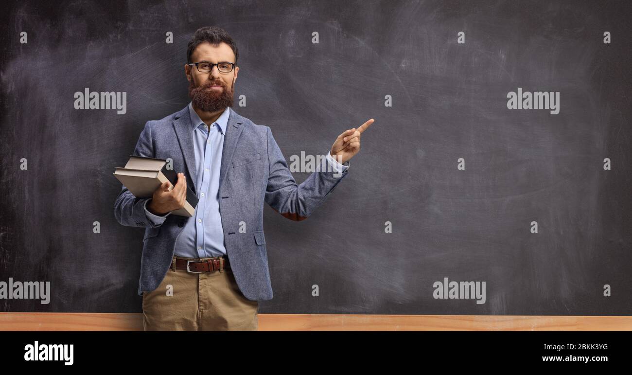 Male teacher holding books and pointing at a chalkboard Stock Photo - Alamy