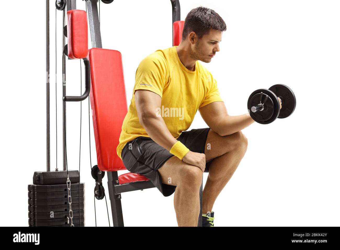 Young man sitting on a fitness machine and exercising with a dumbbell ...