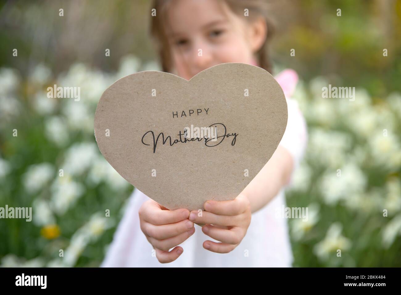 Happy Mother's Day written on a heart-shaped card held by a girl on ...