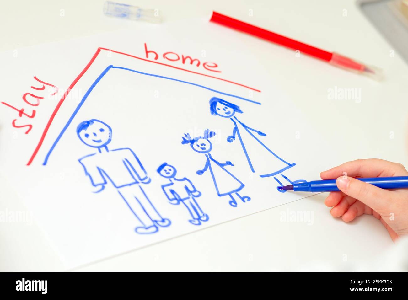 Child is drawing happy family with words Stay Home on white sheet of ...