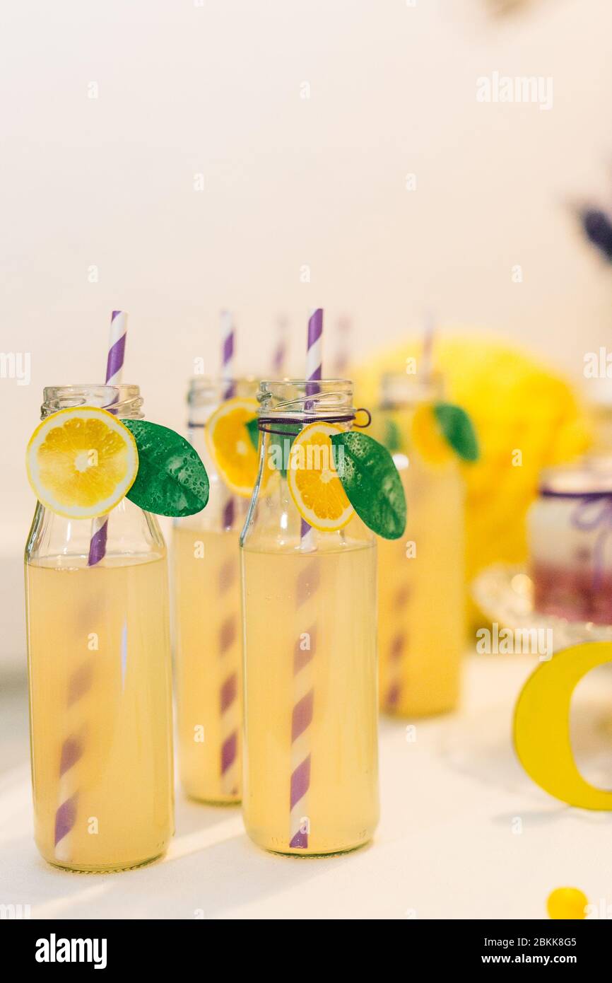 bottle of yellow cool lemonade with lemon and purple drinking straw ...