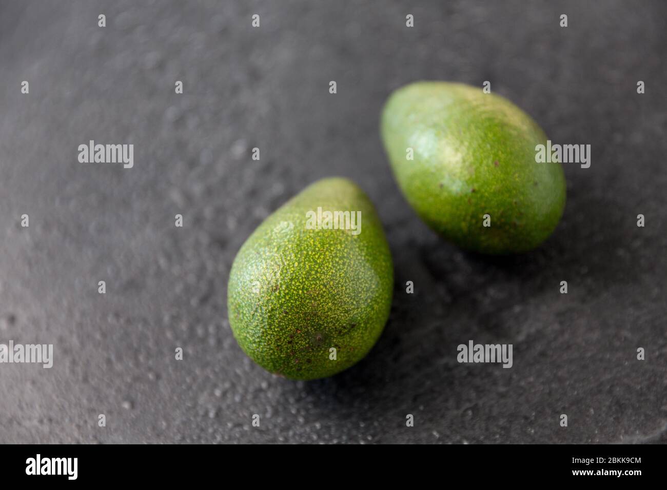 two avocados on wet slate stone background Stock Photo - Alamy