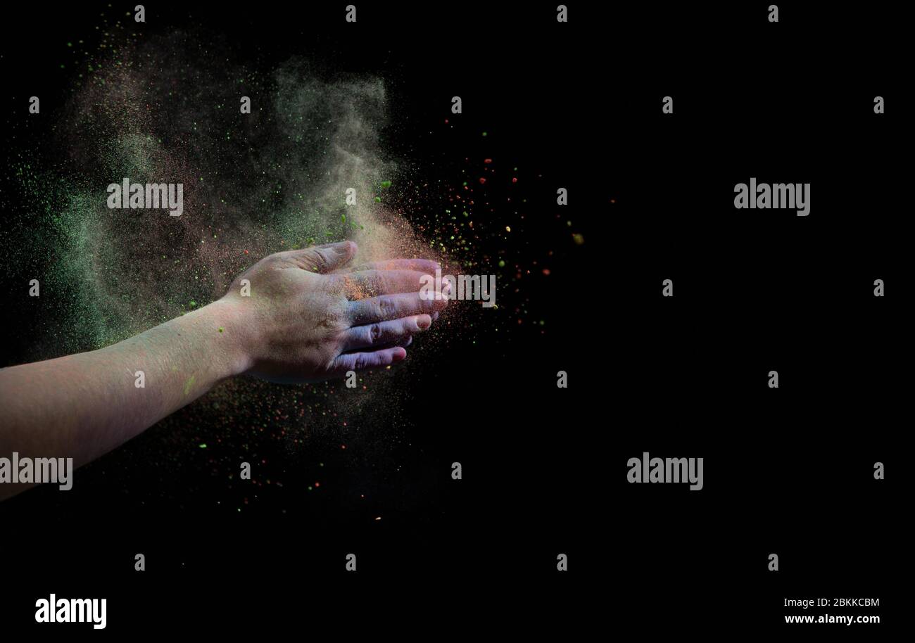 Hands clap, around cloud of multicolored powder Stock Photo - Alamy