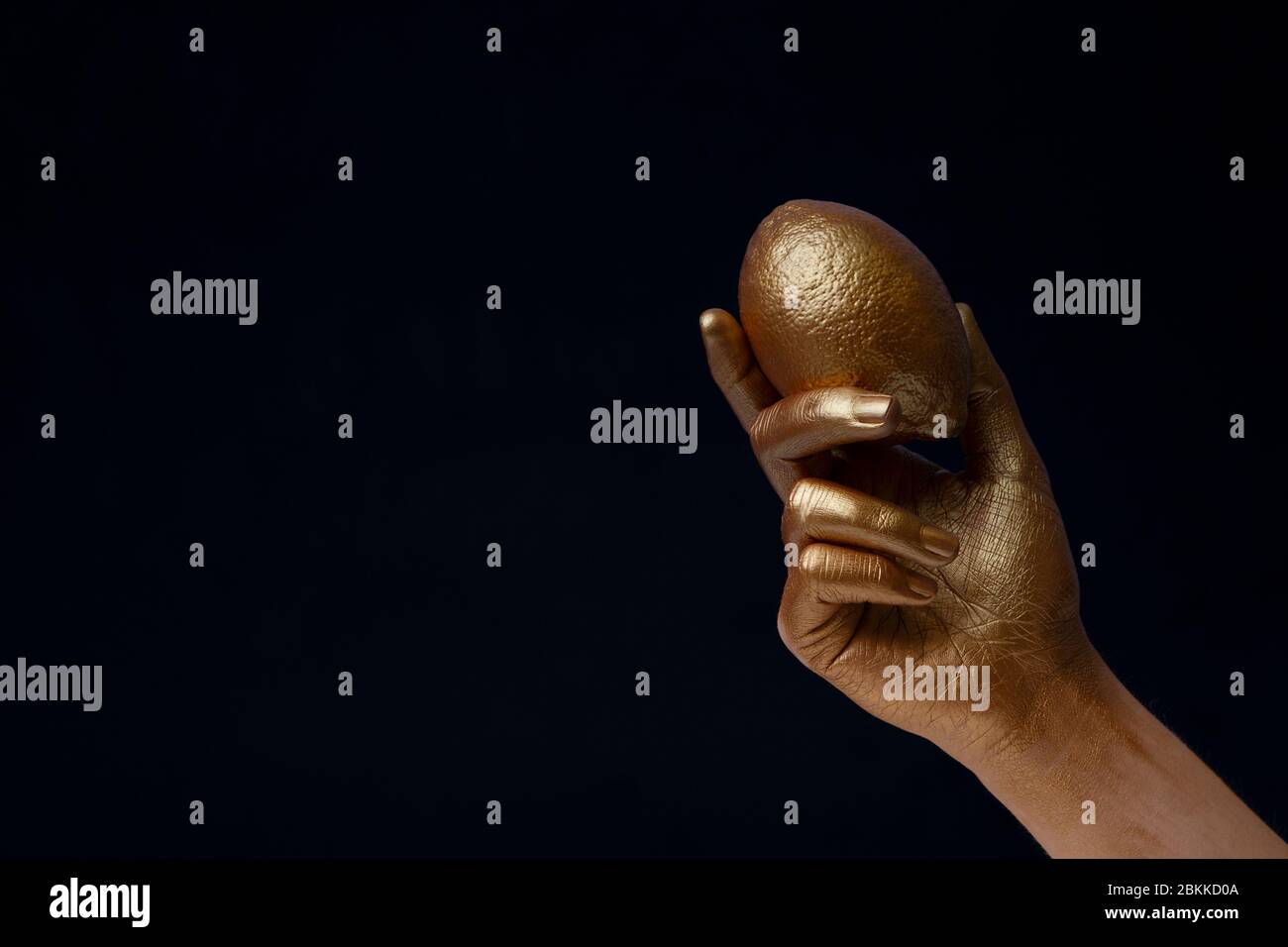 Lemon in hand in gold paint, side view Stock Photo - Alamy