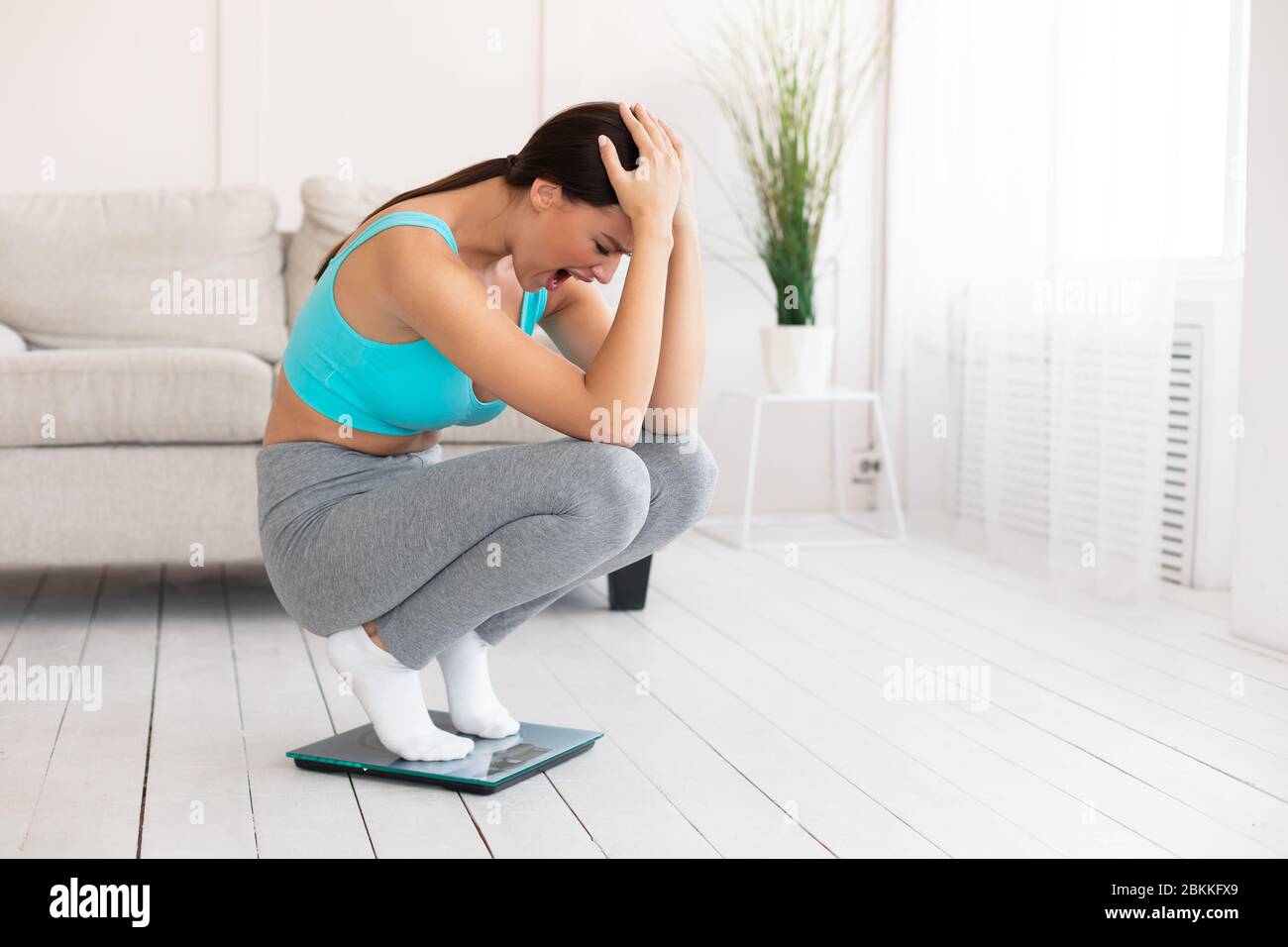 Woman Crying Standing On Scales Gaining Weight At Home Stock Photo - Alamy