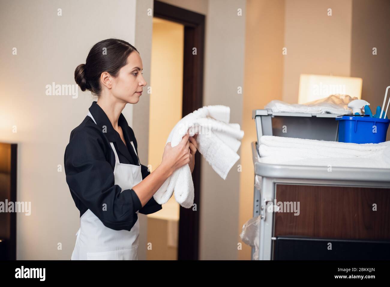 A young happy uniformed maid carrying towels Stock Photo - Alamy