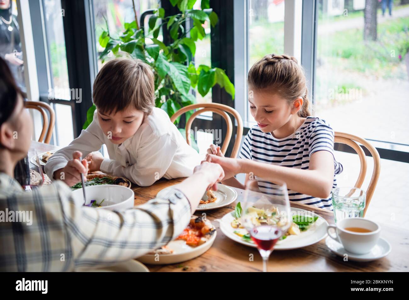 Two kids with their mother sharing food at dinner Stock Photo - Alamy