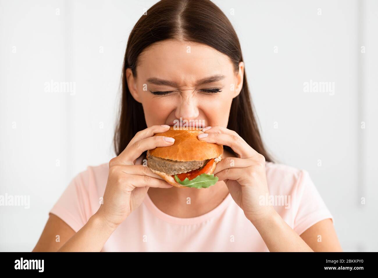 Girl Biting Burger Enjoying Junk Food Having Cheat Meal Indoors Stock ...