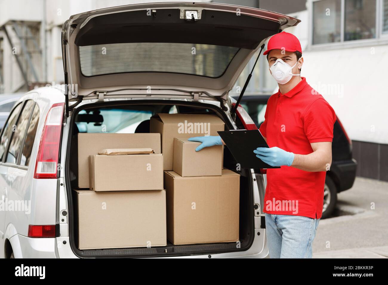 Courier takes out parcel boxes from car Stock Photo - Alamy