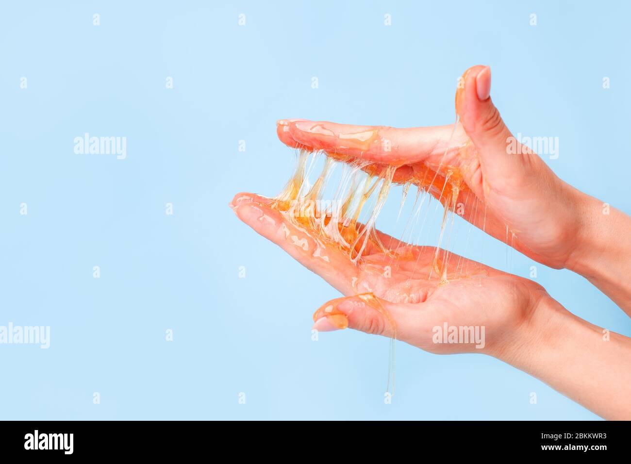 Young girl hands with sticky purple slime on blue background, liquid ...