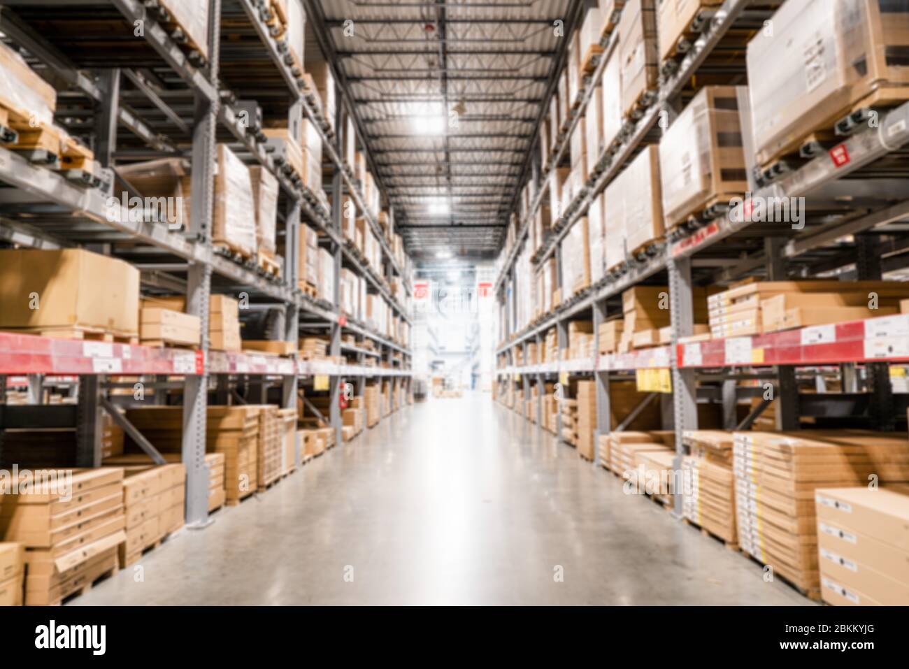 Blurred view of the interior of a warehouse; boxes stacked up high on ...