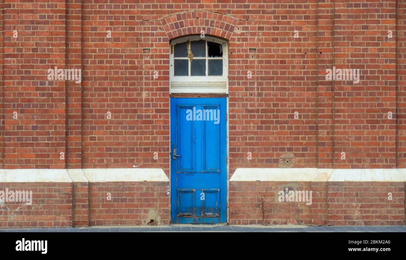 Weathered blue wooden door on a brick wall of industrial factory at ...