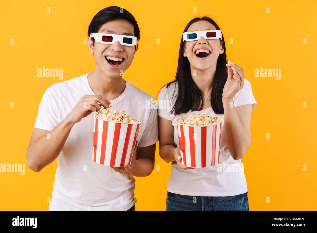 Image of laughing multinational couple in 3d glasses eating popcorn ...
