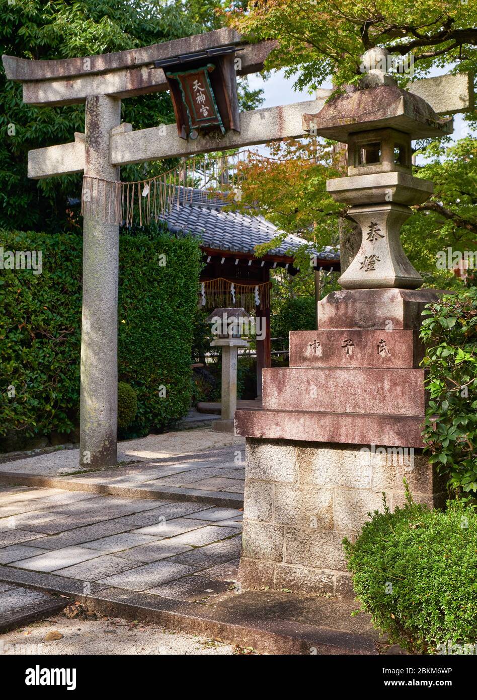 A kaku-doro (square) stone lantern (toro) in front of the torii gate at ...