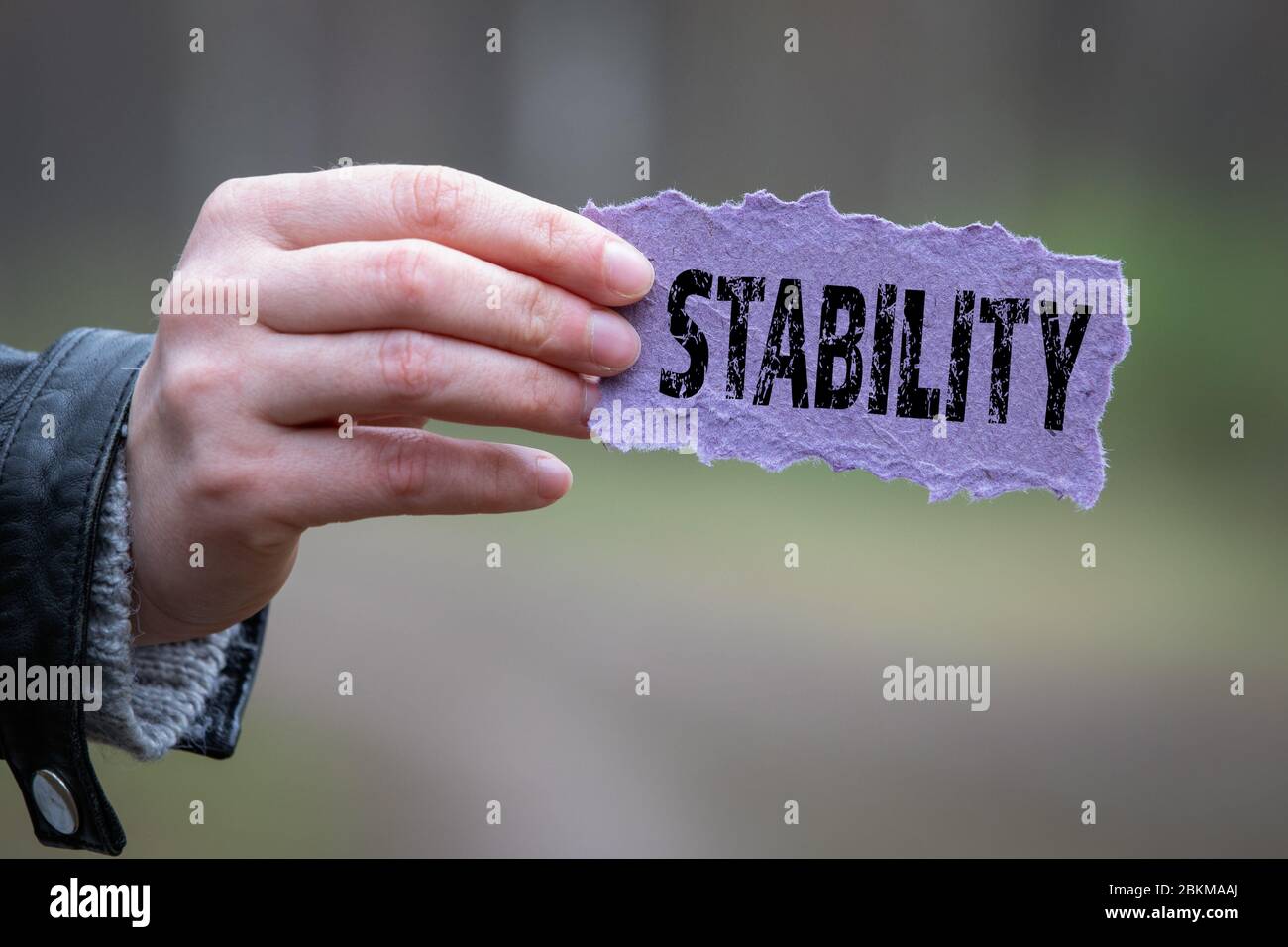 STABILITY. Text on the purple sheet in hand. Green blured background ...