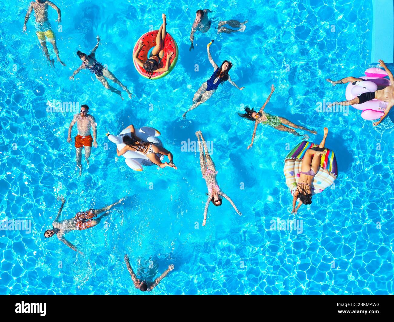 Aerial of friends having party in swimming pool with inflatable ...