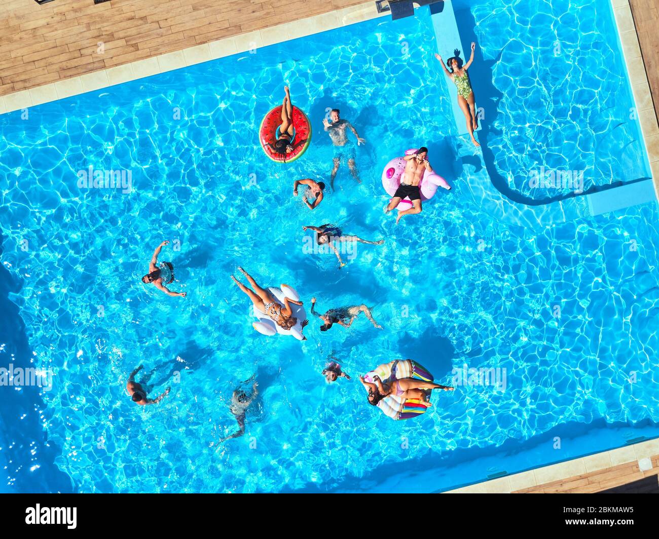 Aerial of friends having party in swimming pool with inflatable ...