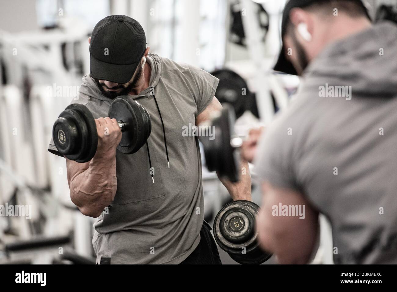 muscular strong man lifting heavy dumbbells pumping biceps in ...