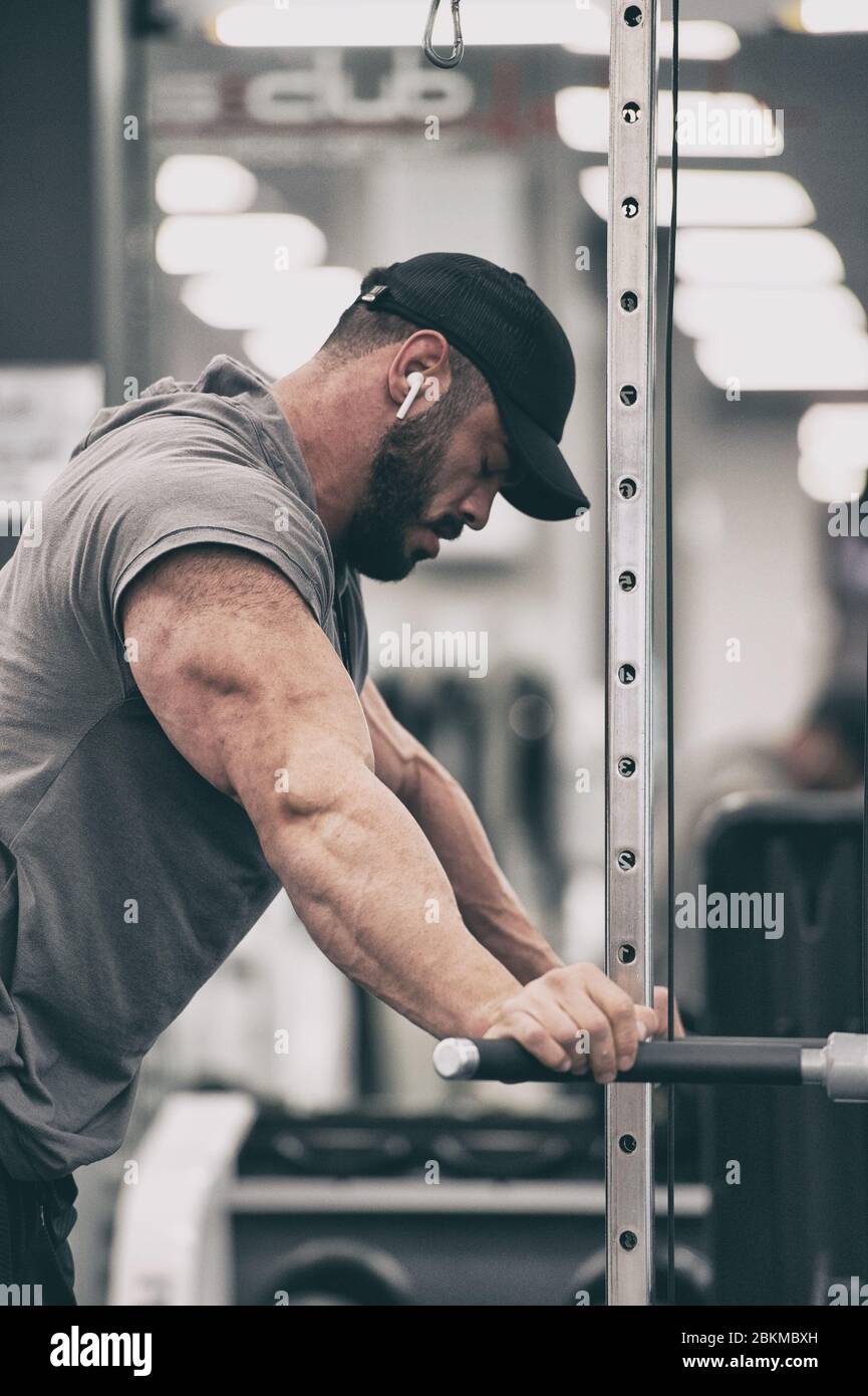 strong young bearded tired man leaning on fitness exercise equipment ...