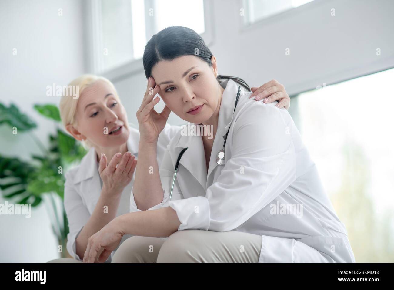 Brunette doctor looking frustrated, her colleague looking concerned ...