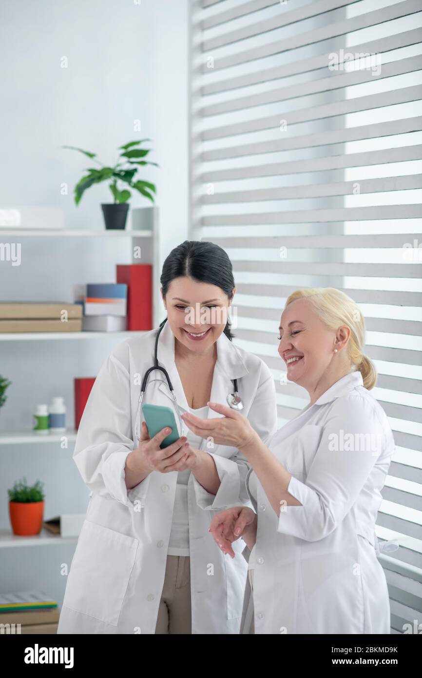 Two doctors in white robes watching a video together Stock Photo - Alamy