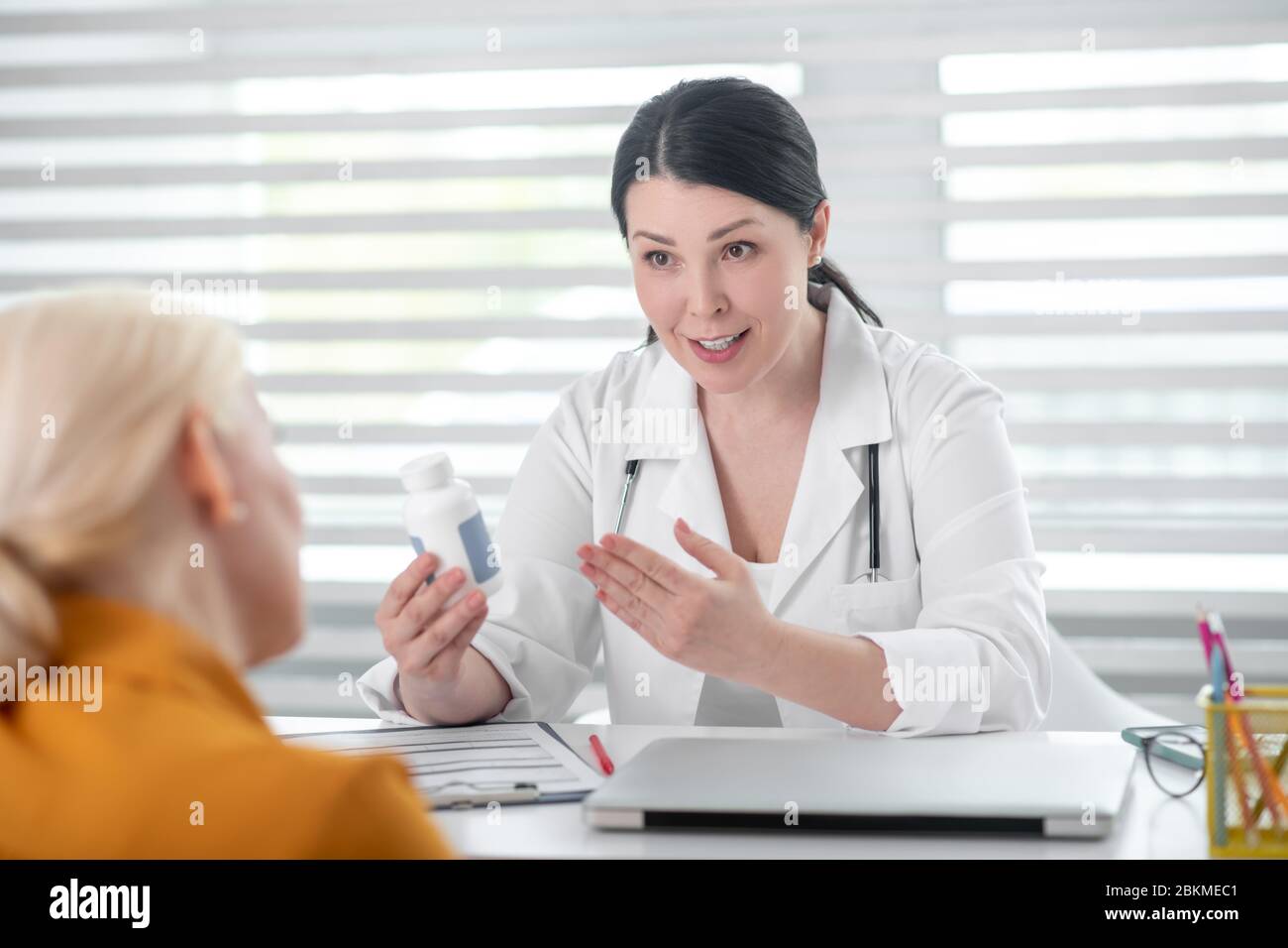 Convincing woman in a white coat with medicine in hand Stock Photo - Alamy