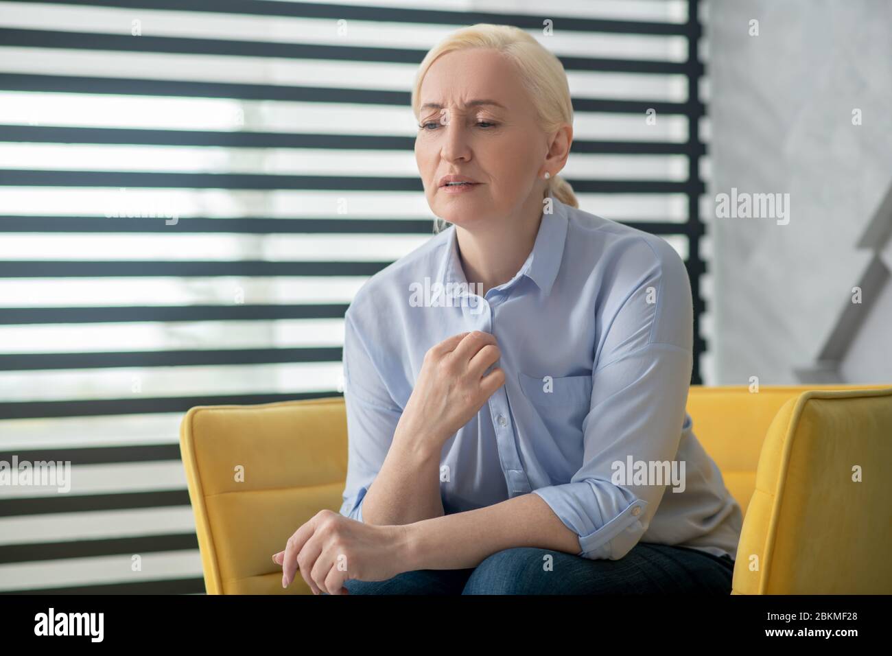 Sad adult woman sitting in a chair near the window Stock Photo - Alamy