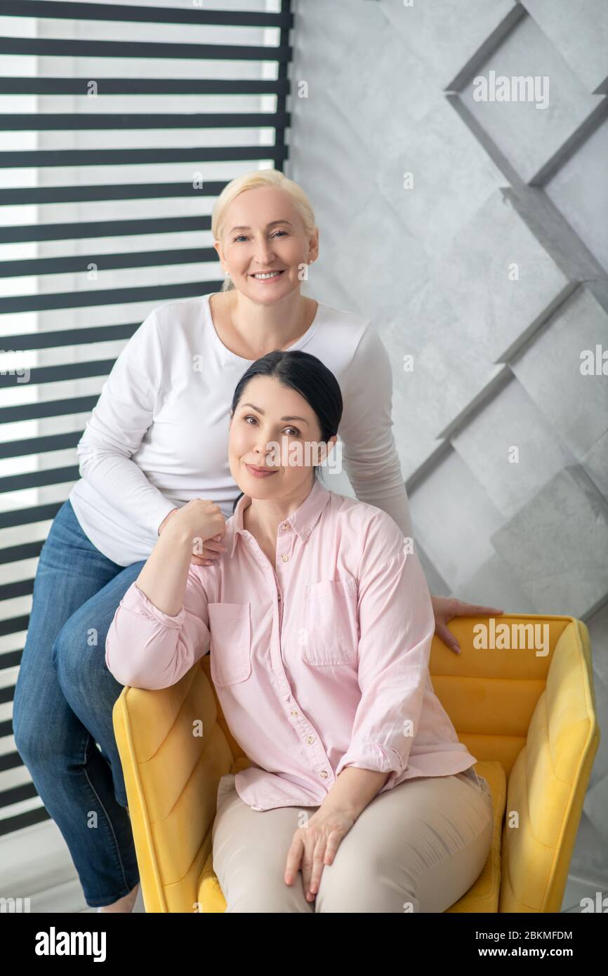 Two adult women in a good mood in a chair Stock Photo - Alamy