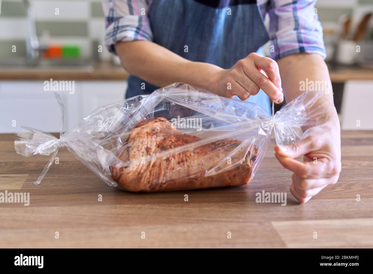 Woman packs pork leg marinated with spices in baking sleeve Stock Photo ...
