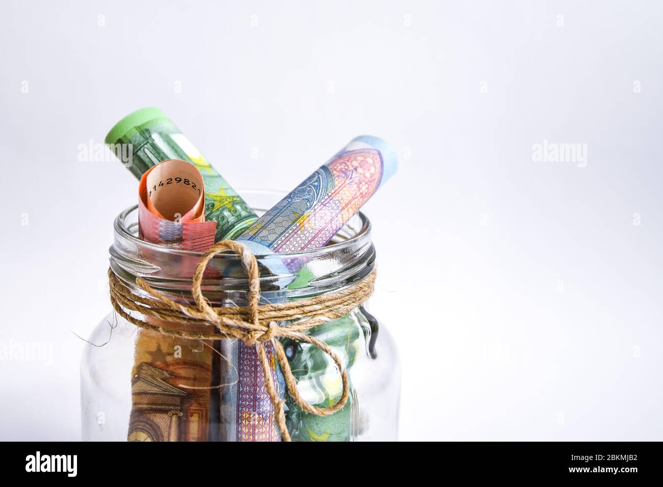 Glass jar with euro notes isolated on white background, euros rolled up ...
