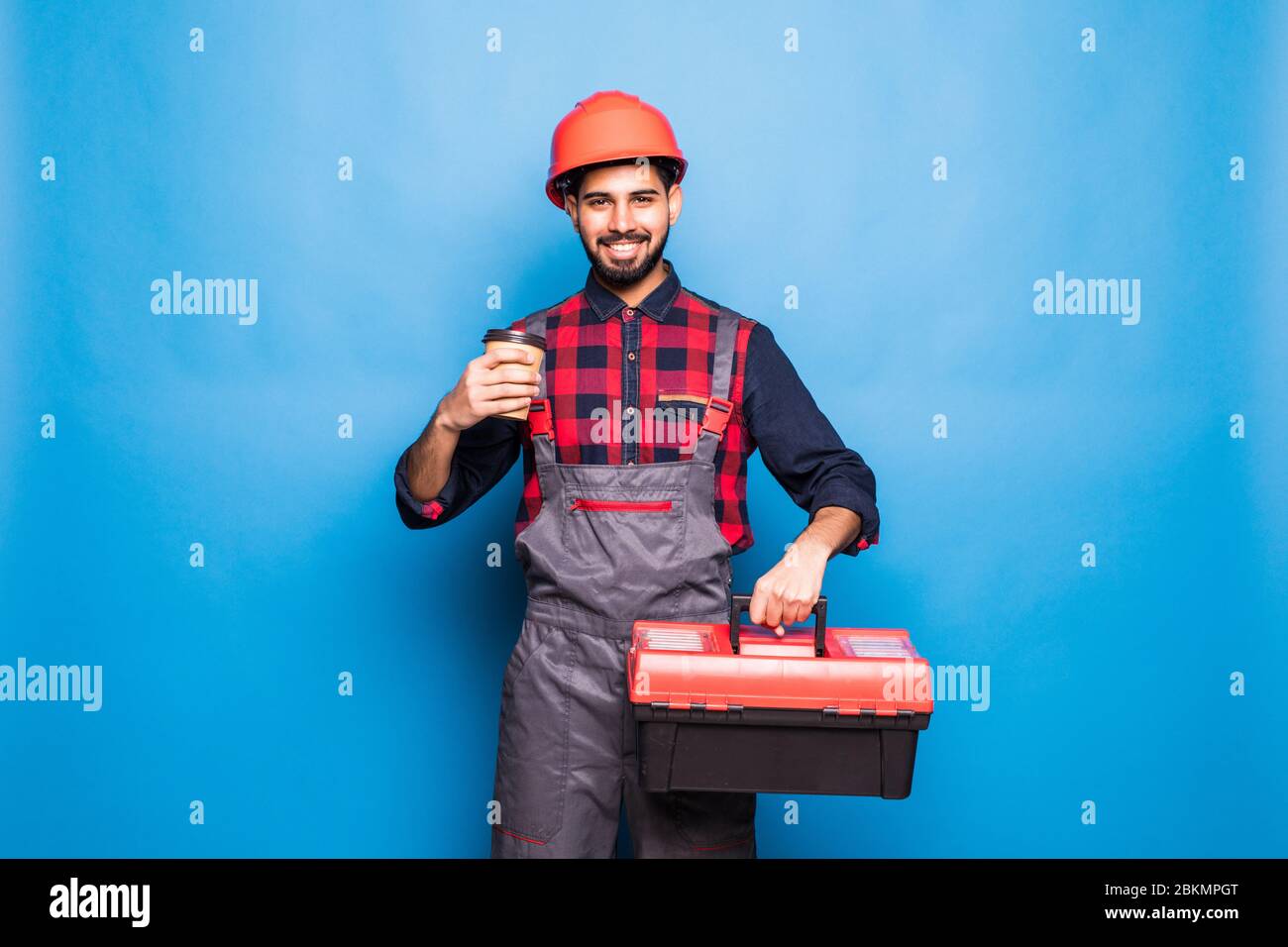 Portrait of indian happy man holding a red tool box isolated on blue ...