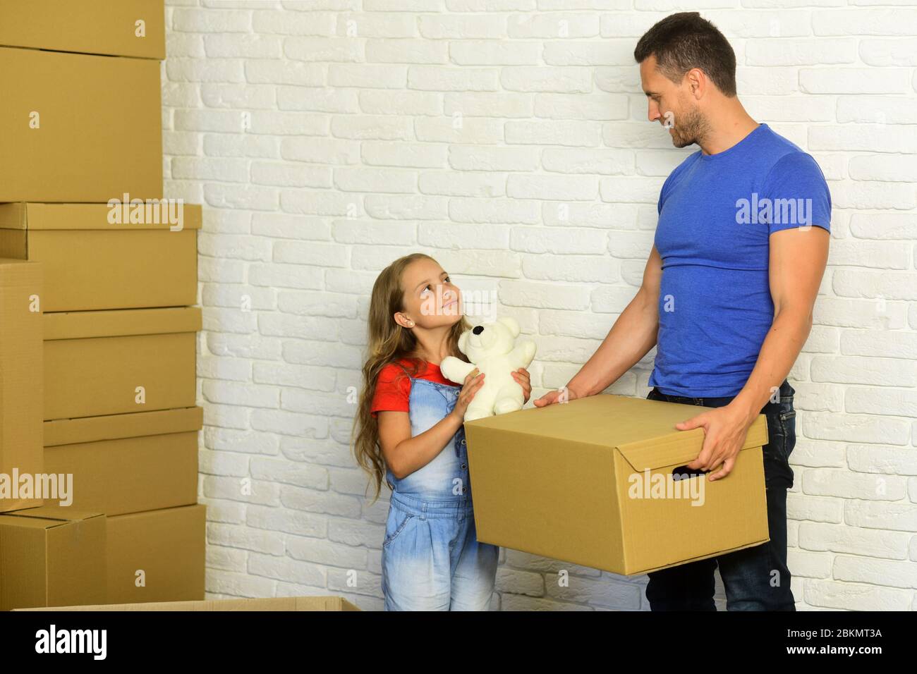 New home and family concept. Daughter and father hold box, white teddy ...