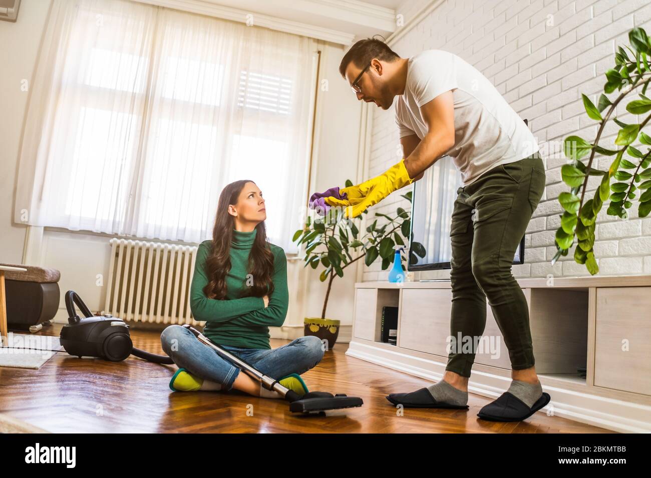 Woman is lazy. Man is telling her to continue cleaning their apartment ...