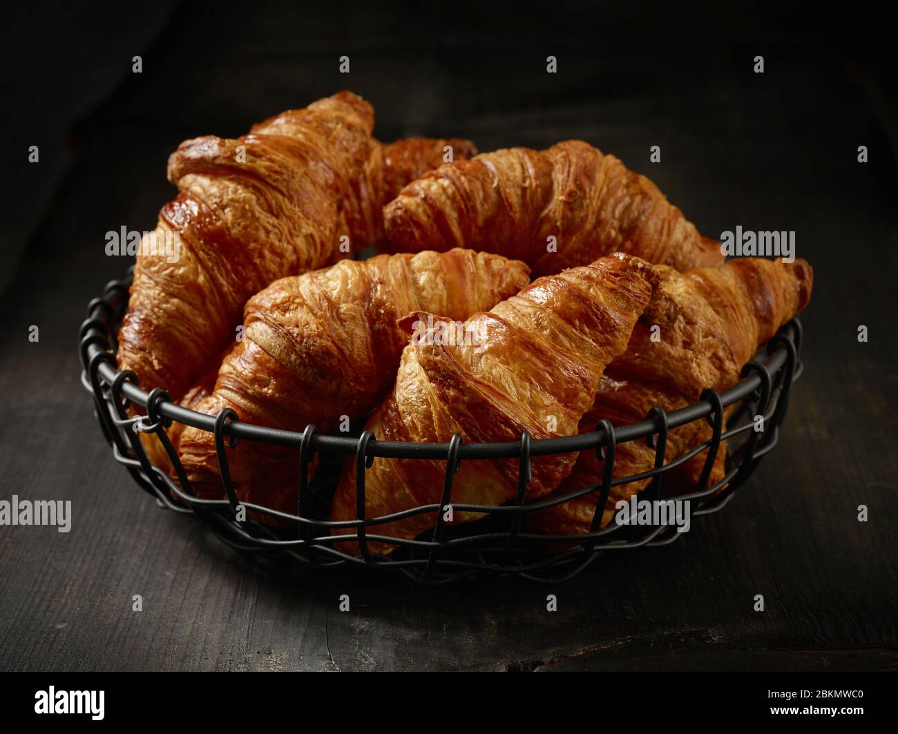 freshly baked croissants in black basket on dark wooden kitchen table ...