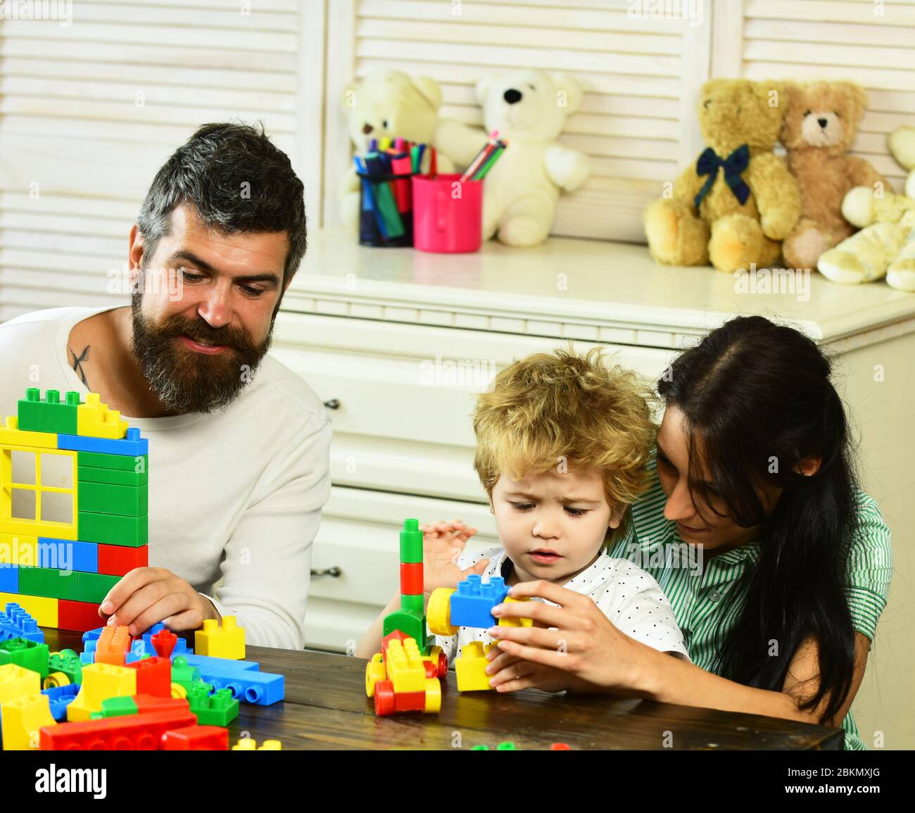 Young family spends time in playroom. Parents and son with curious ...