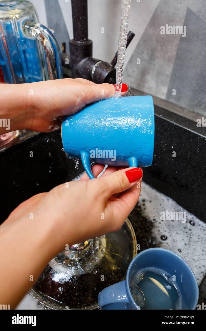 Hands with sponge wash the cup under water, housewife woman in washing ...